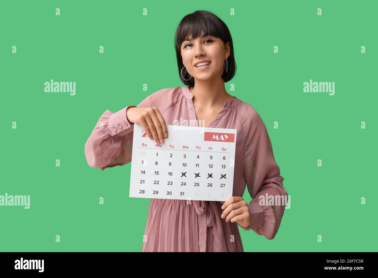 Pretty young woman holding calendar with marked days on green ...