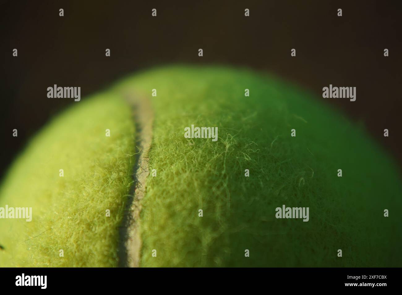 A macro shot of a green tennis ball, showing the fuzzy covering of the ...