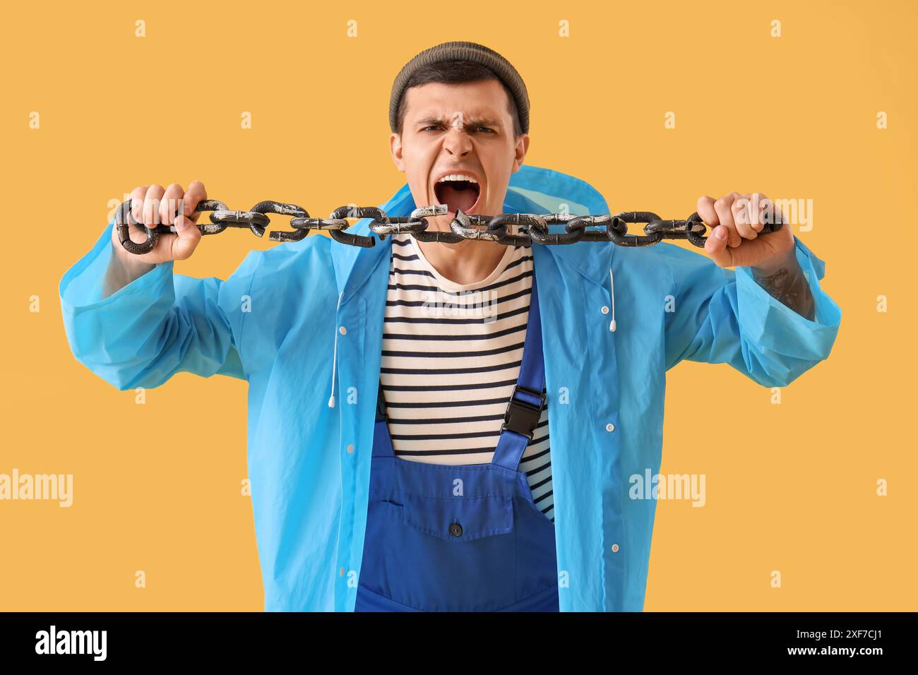 Angry young sailor in raincoat with chain on yellow background Stock ...