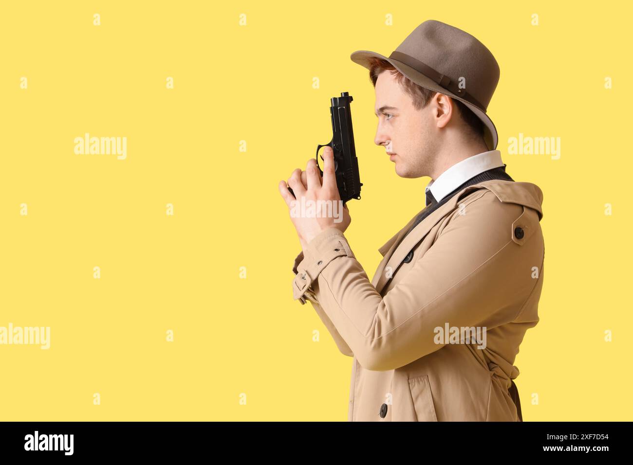 Male spy with gun on yellow background Stock Photo - Alamy