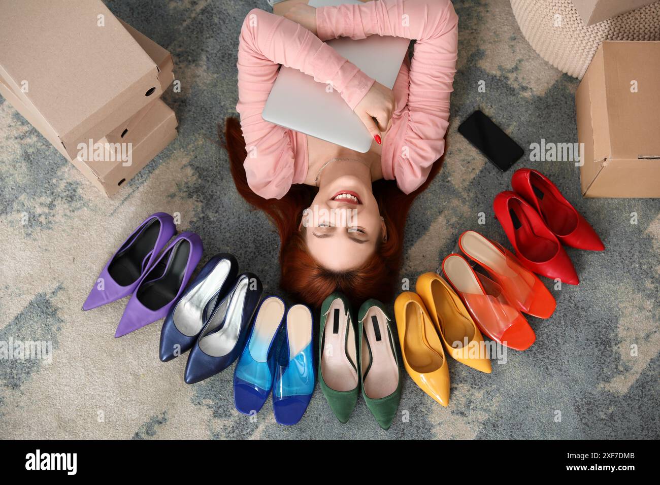 Young woman lying on floor with laptop and mobile phone among high ...