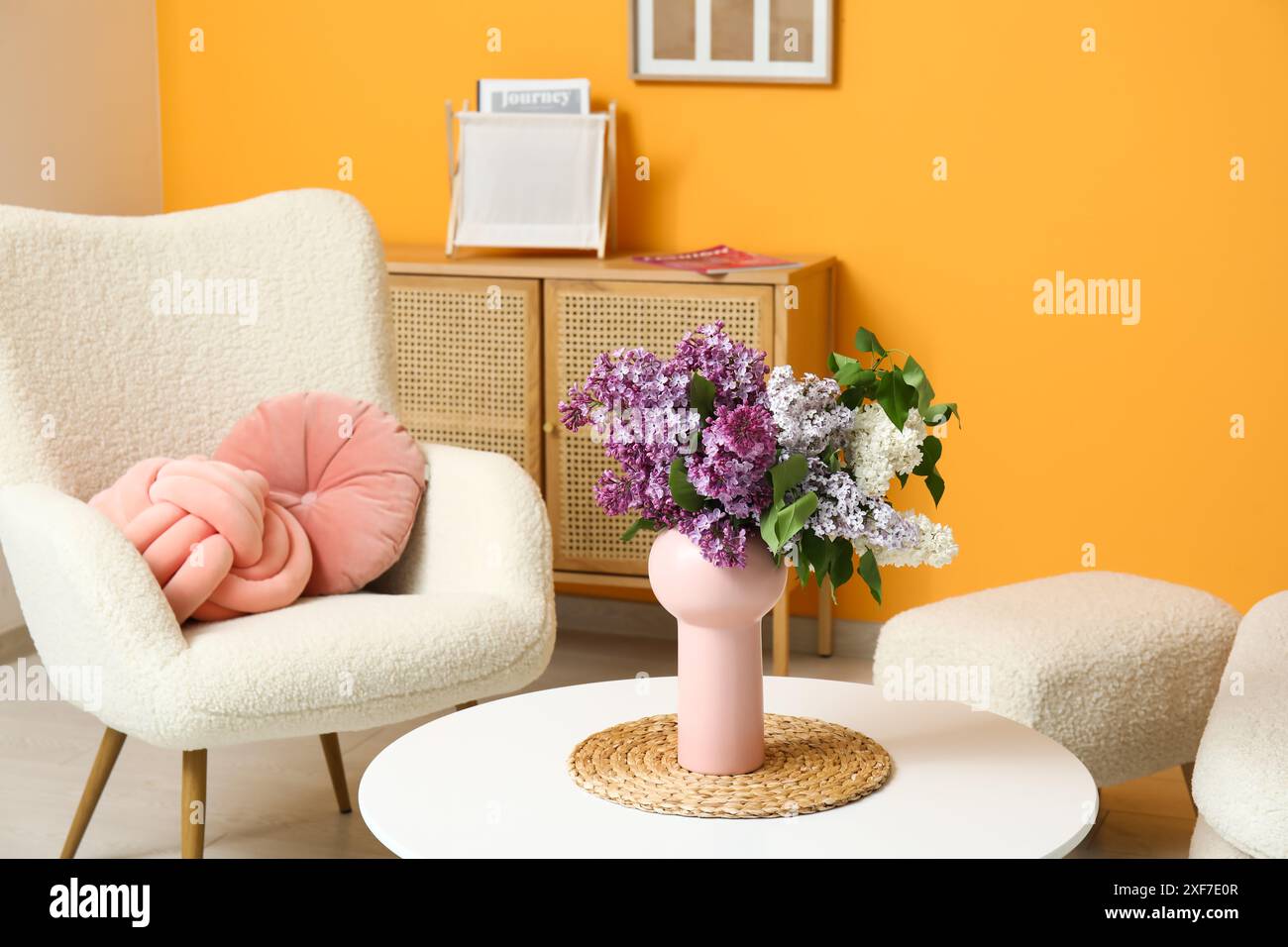 Interior of living room with bouquet of lilacs branches on coffee table ...