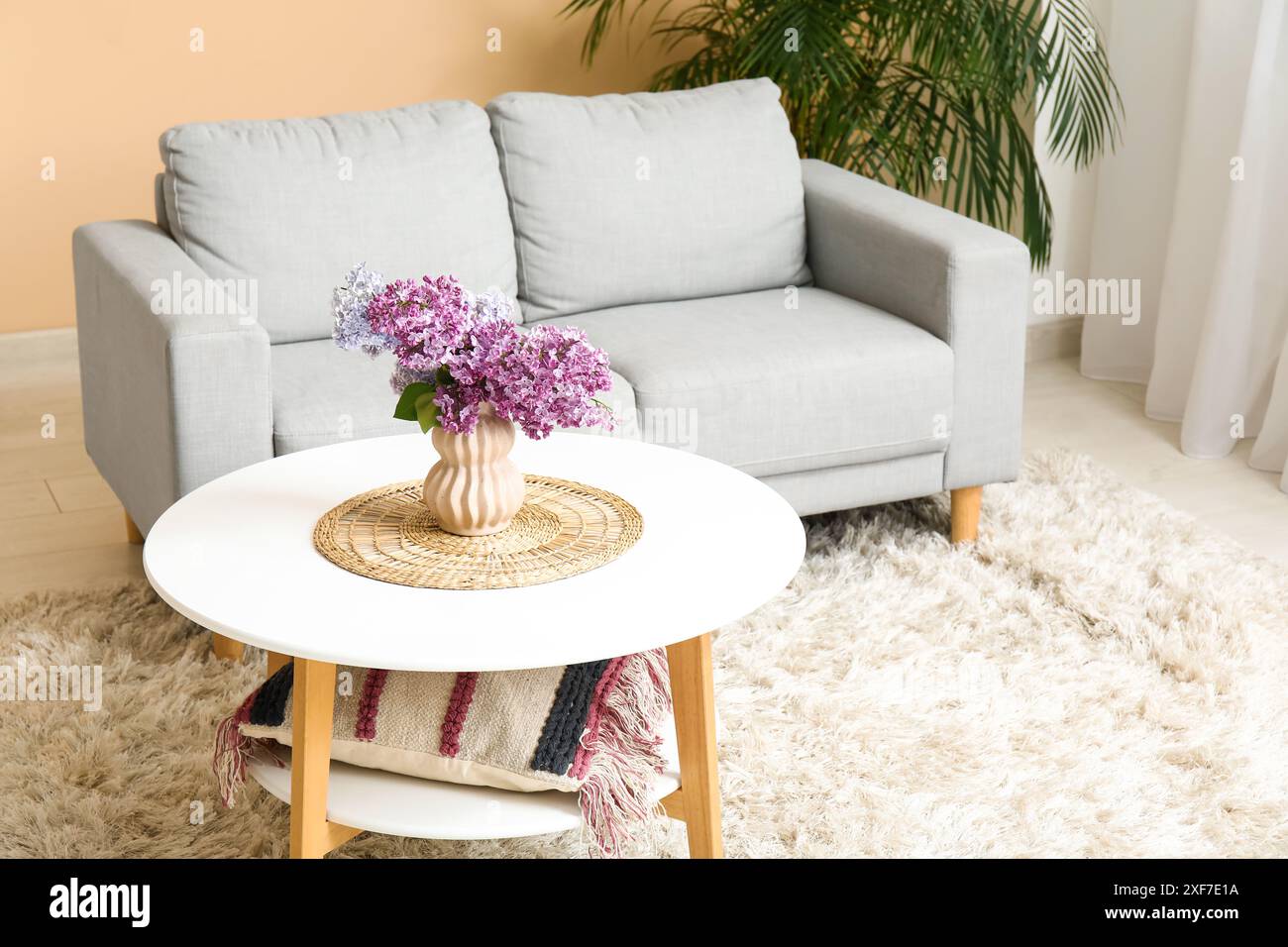 Interior of living room with bouquet of lilacs branches on coffee table ...