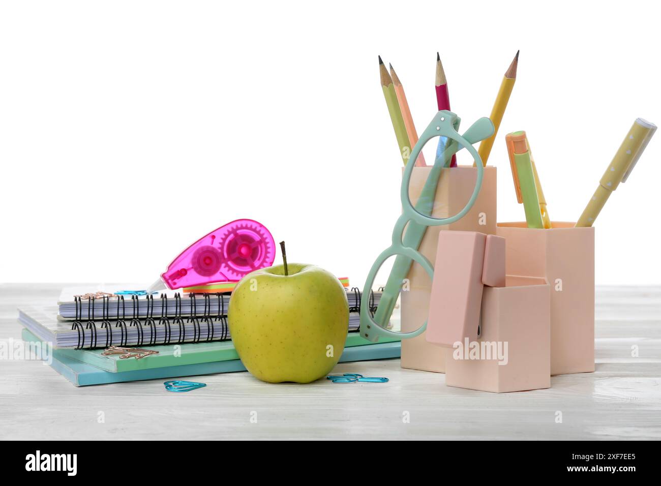 Green apple and school supplies with eyeglasses on table against white ...