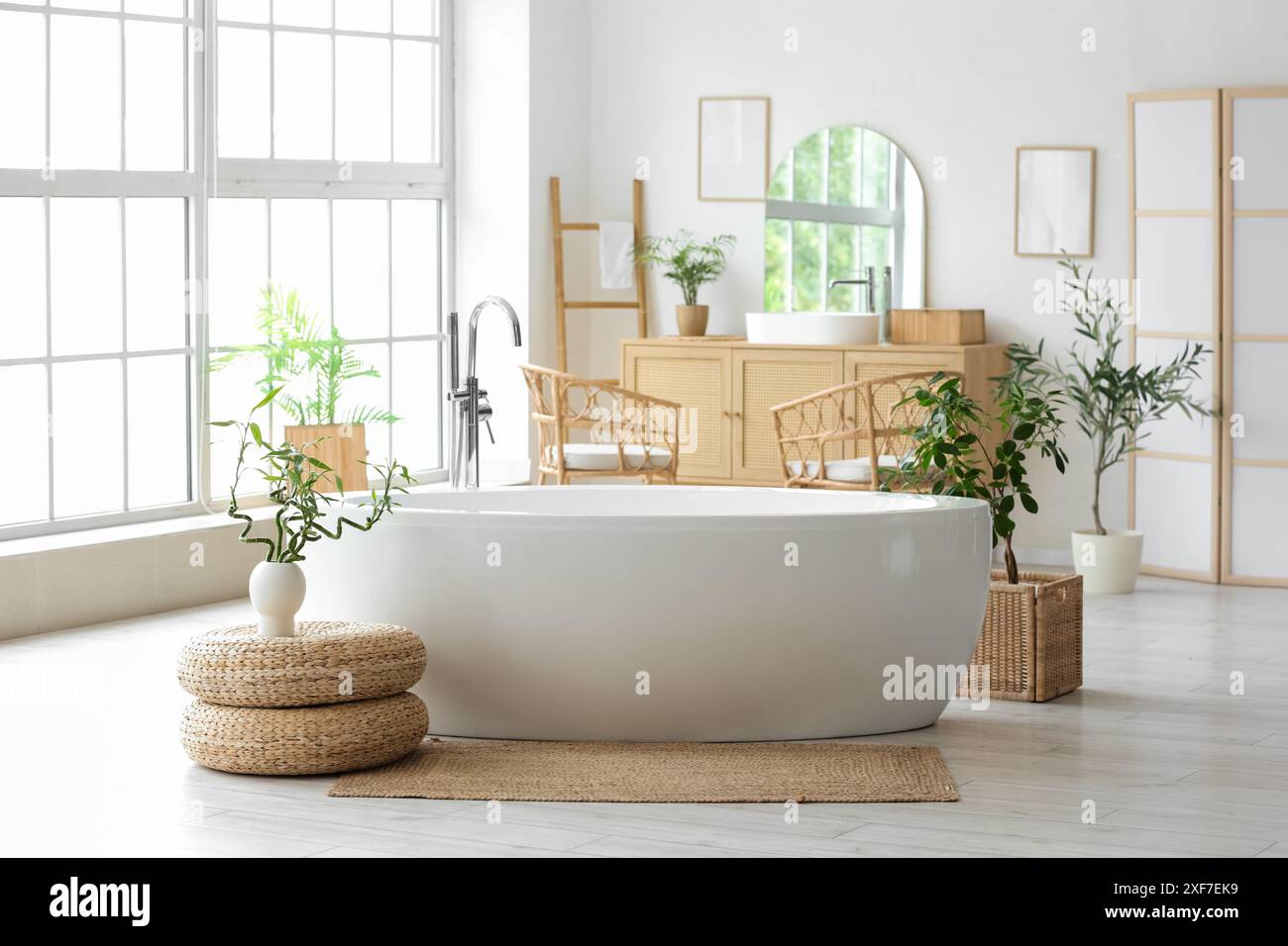 Wicker poufs, houseplant and bathtub in interior of modern bathroom ...