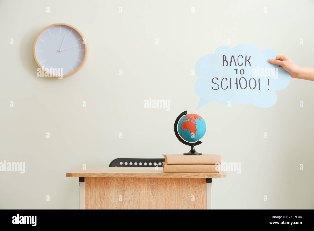 Woman holding speech bubble with text BACK TO SCHOOL near desk in ...