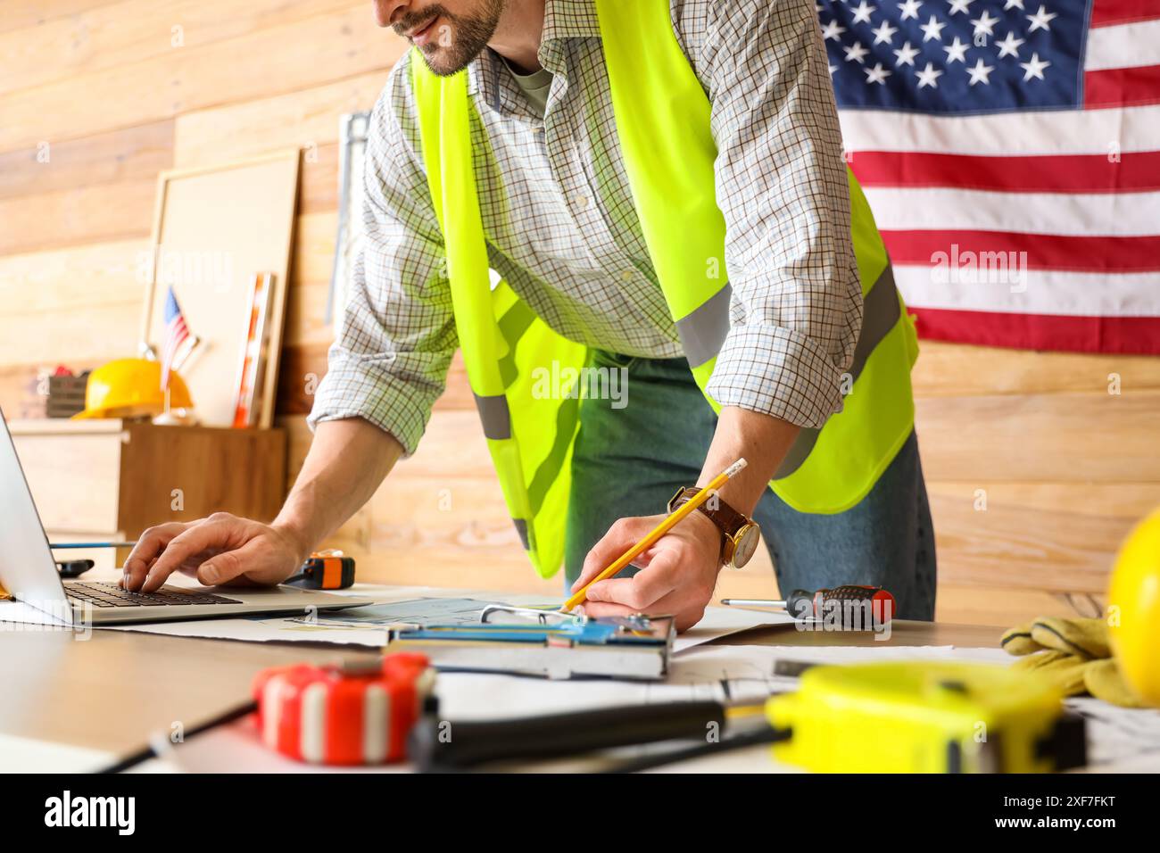 Male architect working with laptop and house plan in workshop. Labour ...