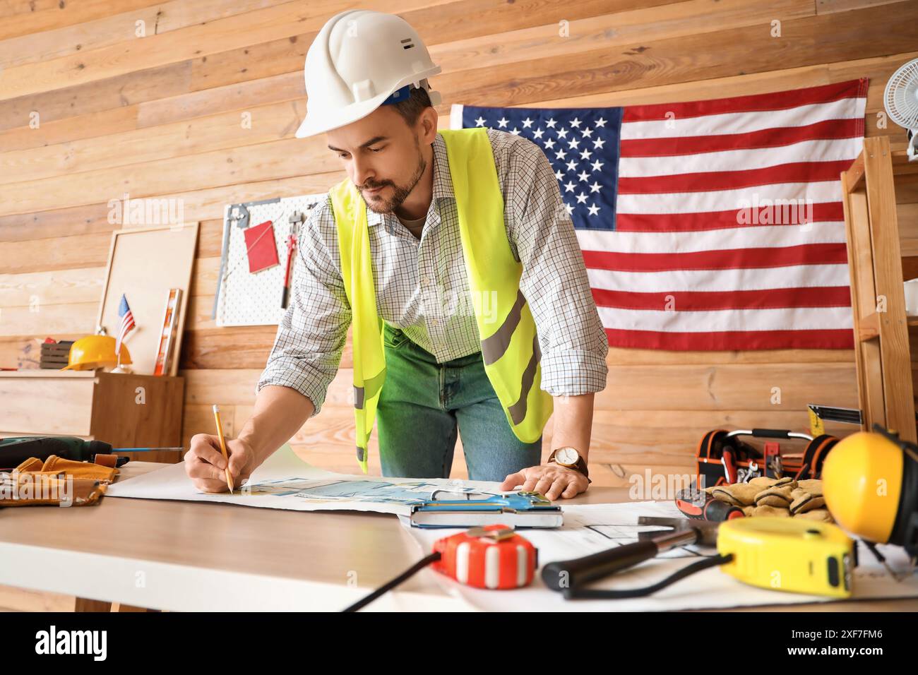 Male architect working with house plan in workshop. Labour Day ...