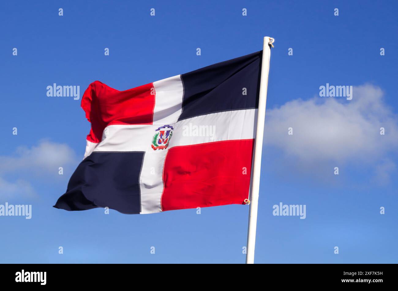 Red and blue flag of the Dominican Republic waiving against blue sly ...