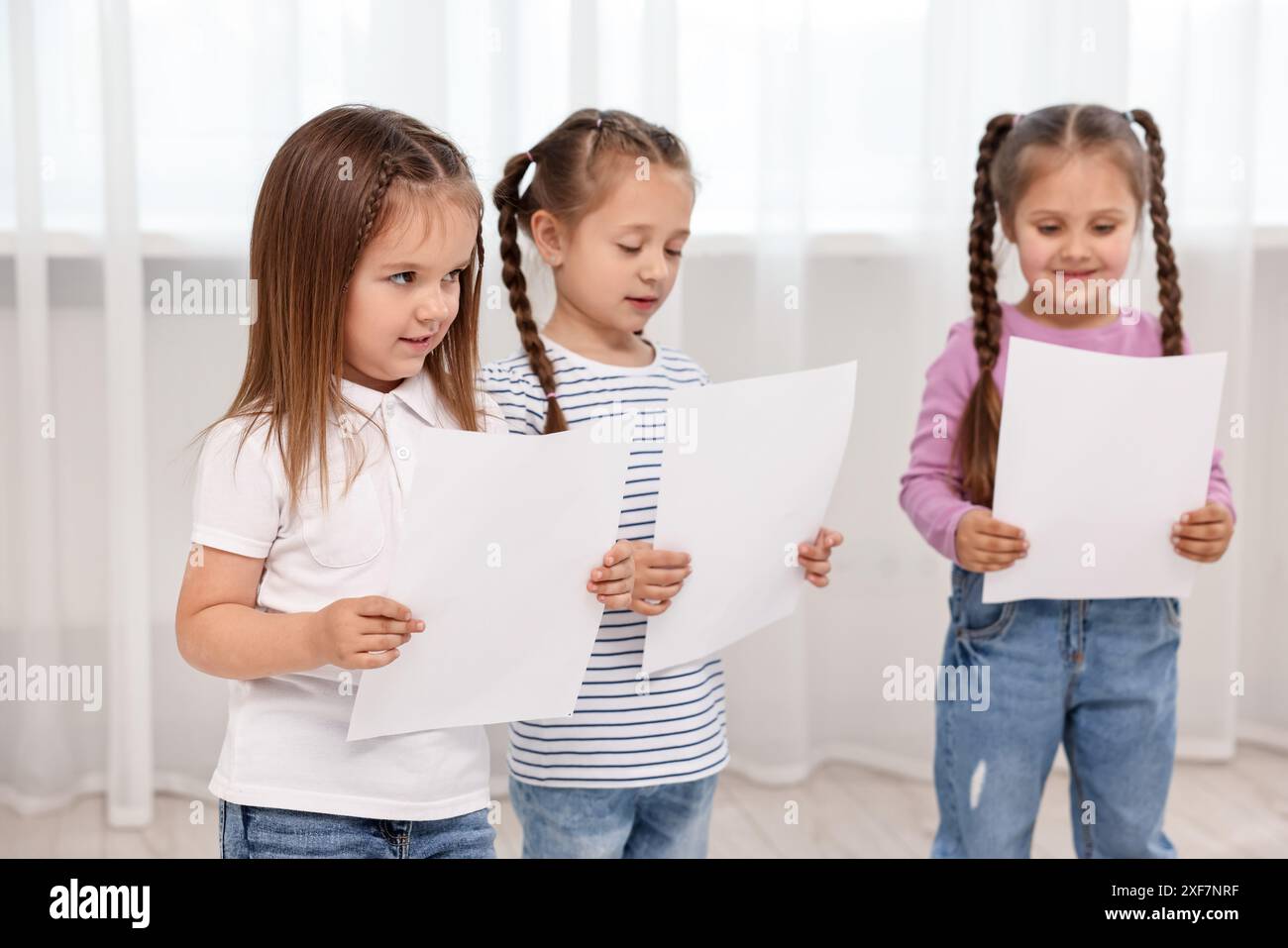 Cute little children with sheets of paper singing indoors Stock Photo ...
