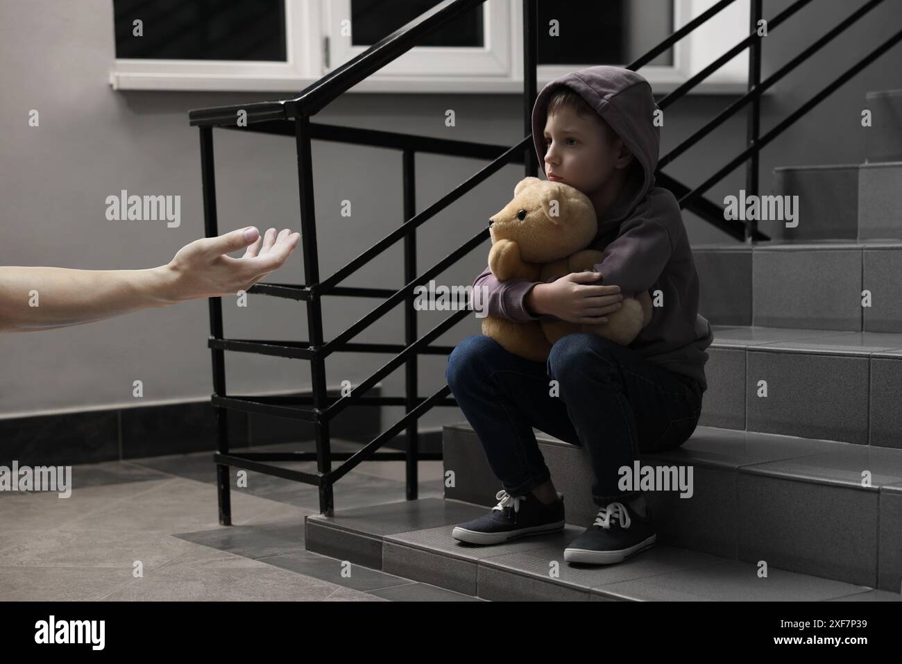 Sad little child looking at outstretched man's hand indoors. Trust ...