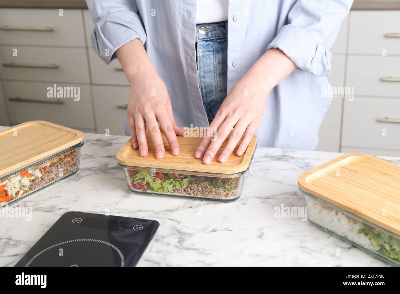 Healthy food. Woman closing glass container with meal at white marble ...