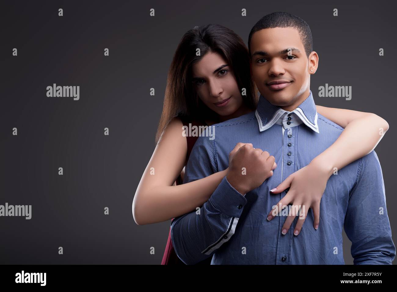 Young couple in love, hugging in trendy clothes against a grey ...