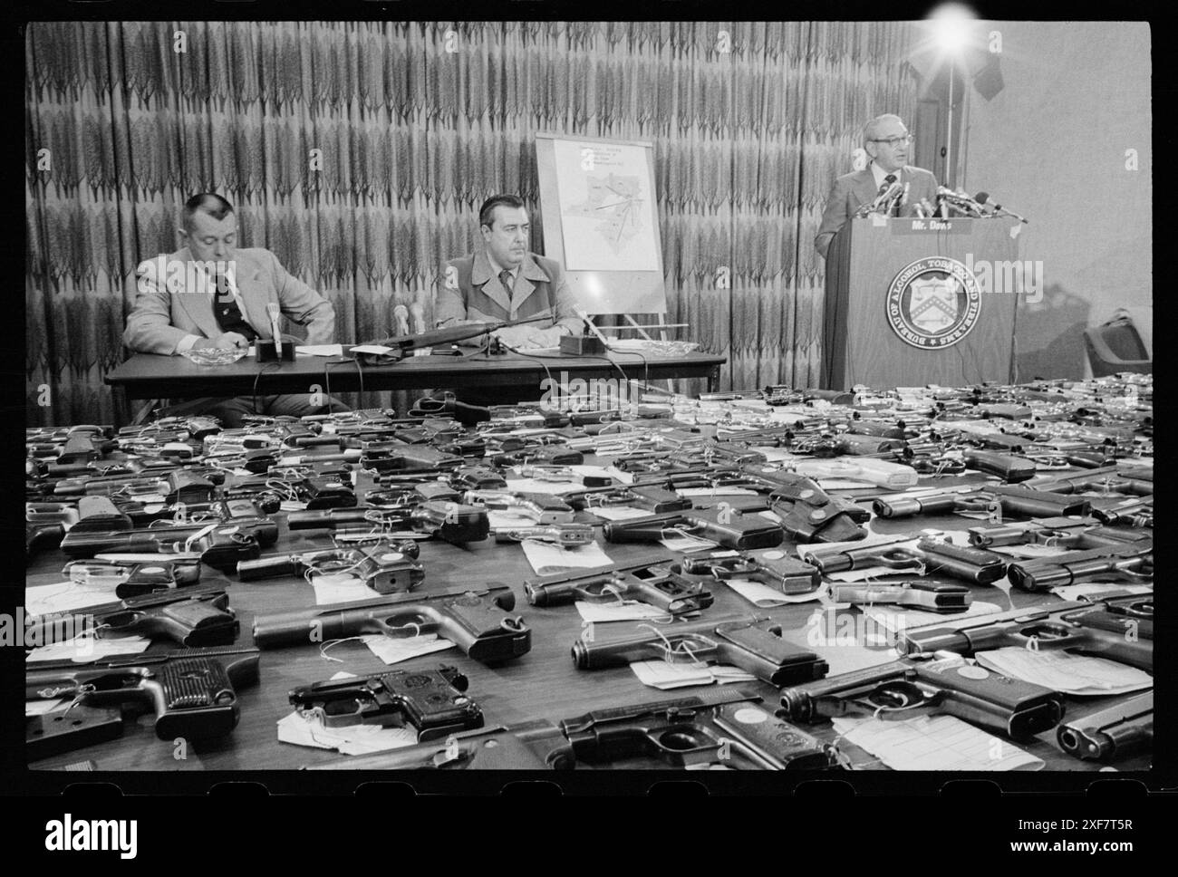 Unidentified ATF officials sit at a table, while another speaks at a ...