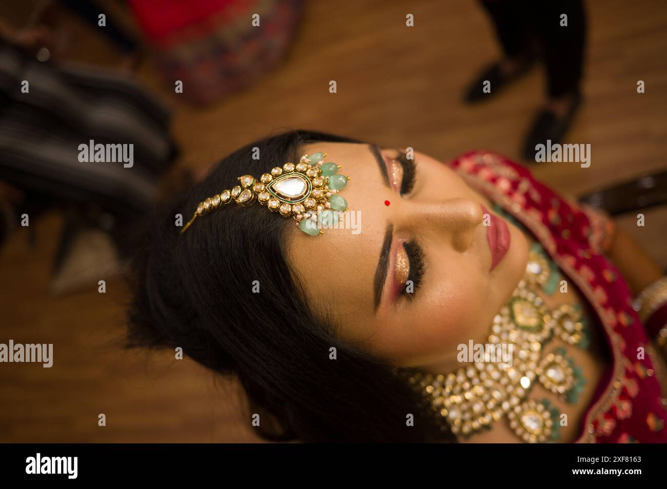 A young Indian bride getting makeup applied for a traditional Indian ...