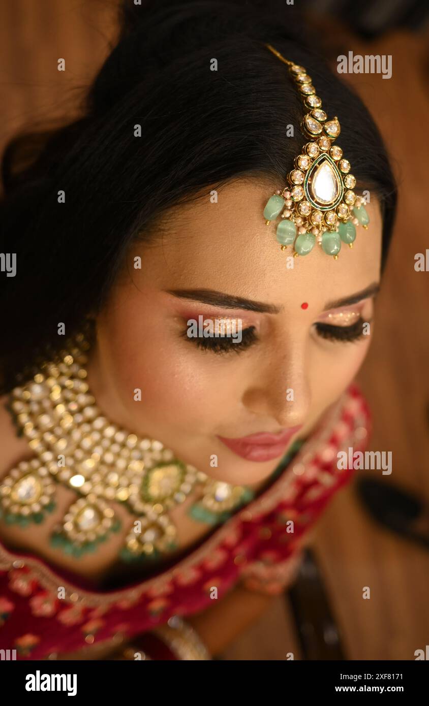 A young Indian bride getting makeup applied for a traditional Indian ...