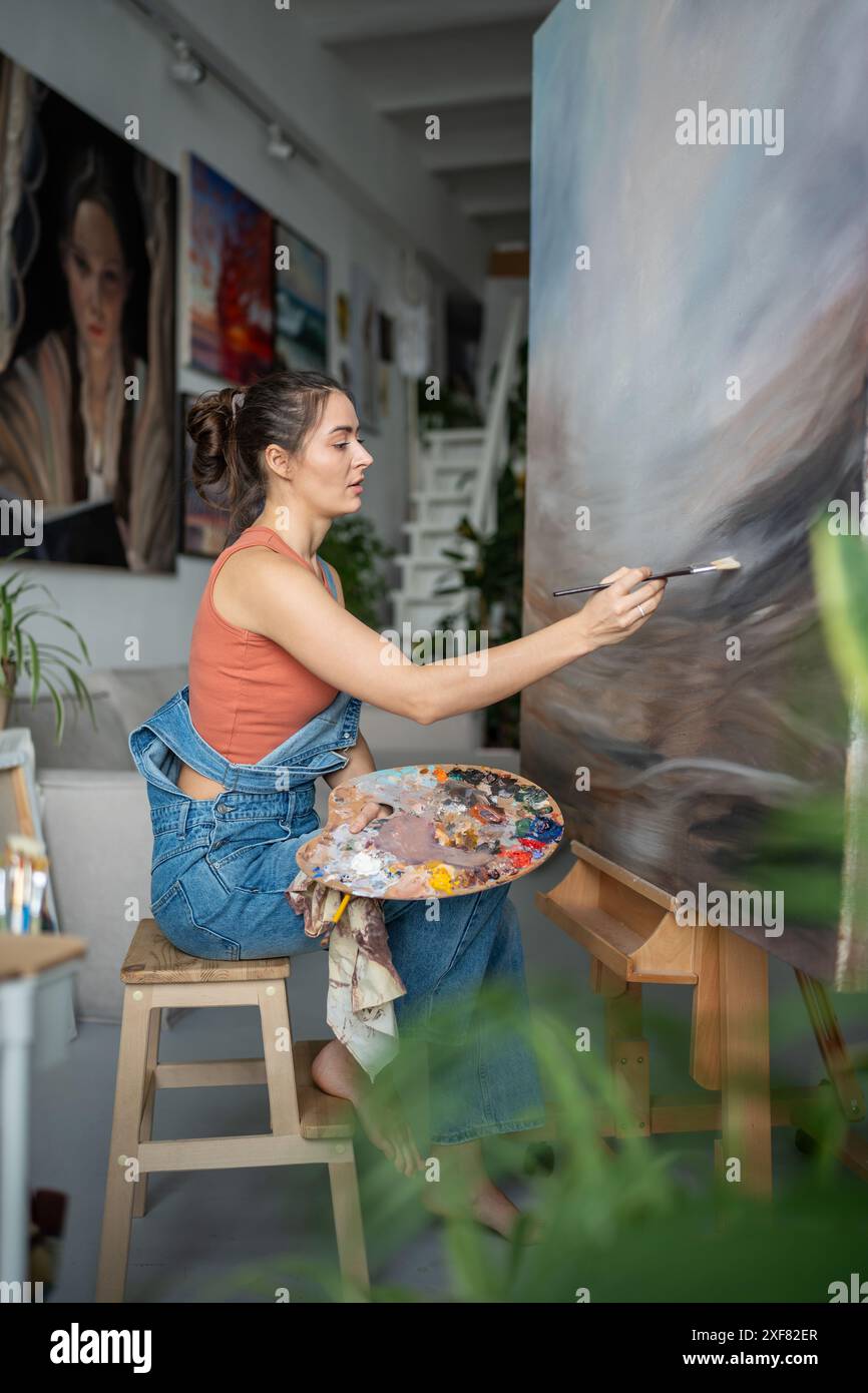 Focused modern female artist in home art studio carefully painting ...