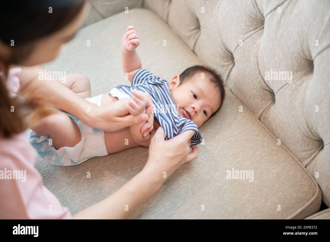 A caring mom is changing her newborn baby's clothes and diaper, or ...