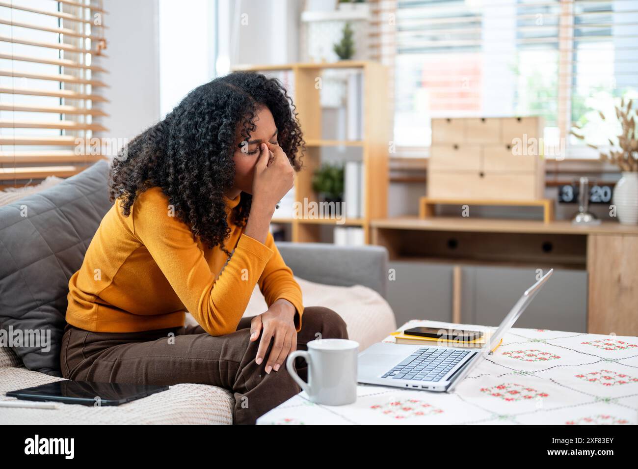 A stressed, unhappy Black woman is working from home, sitting in the ...