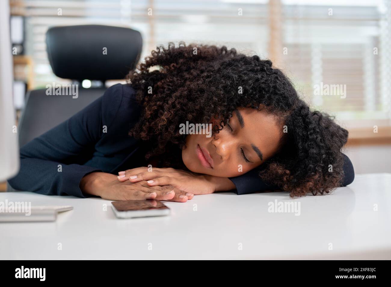A tired, sleepy Black businesswoman taking a nap at her desk in the ...