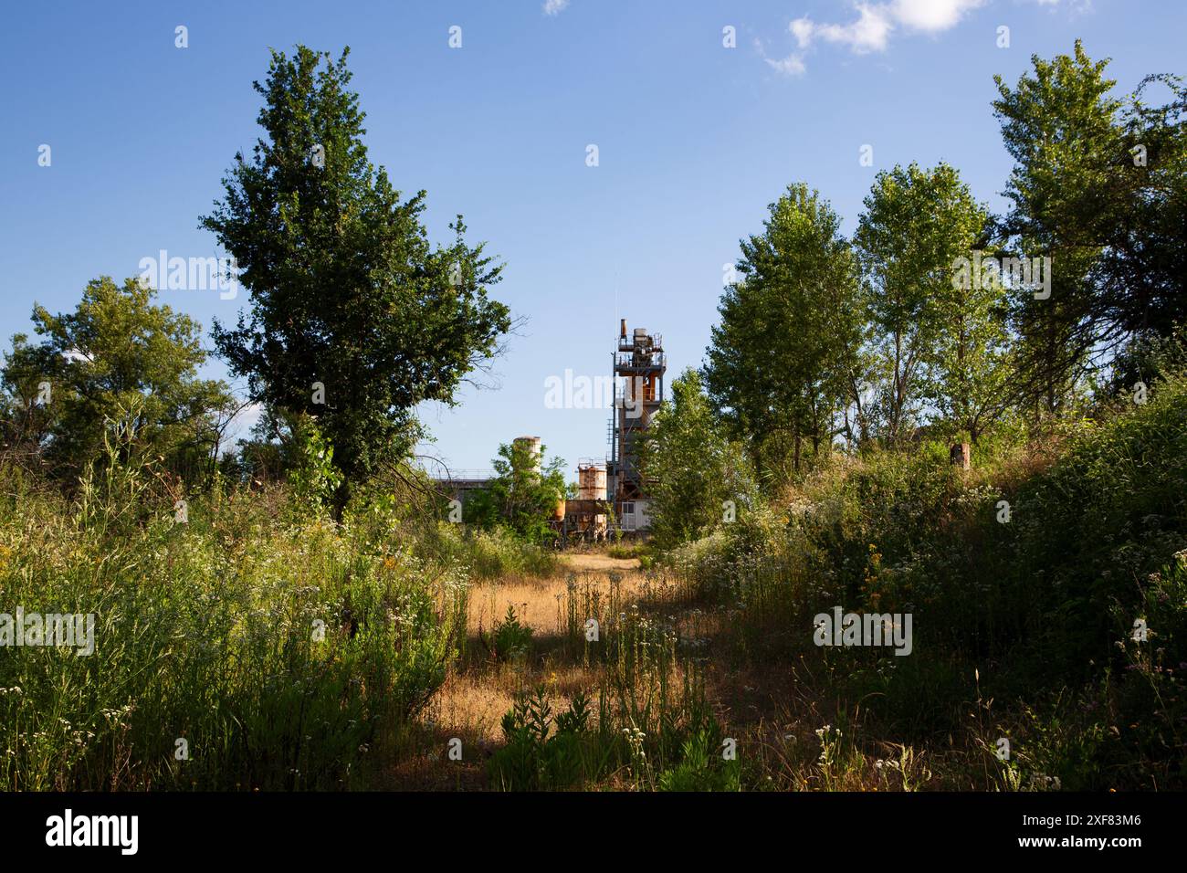 Derelict industrial site with abandoned buildings and wild vegetation ...