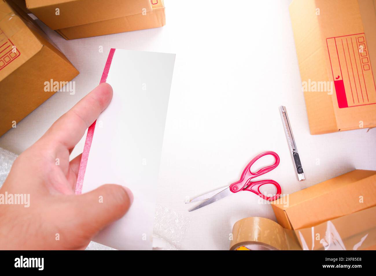 Blank white bill in a hand with goods boxes for packing , goods ...