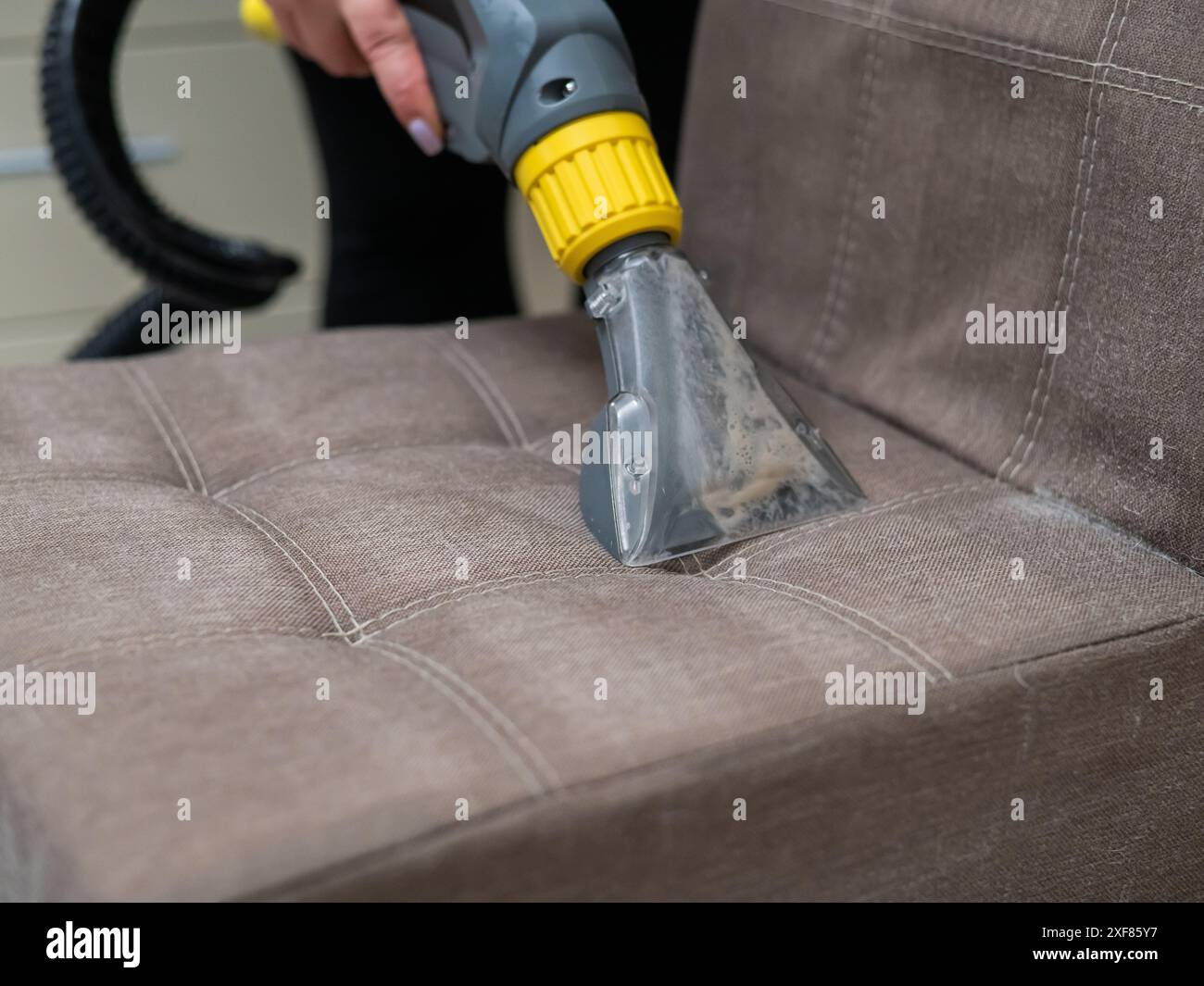 Woman cleaning a fabric chair with a professional washing vacuum ...