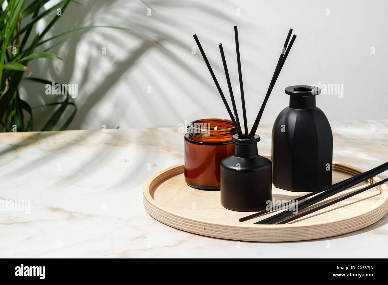 Black Reed Diffuser, Amber Candle, and Wooden Tray on White Surface ...