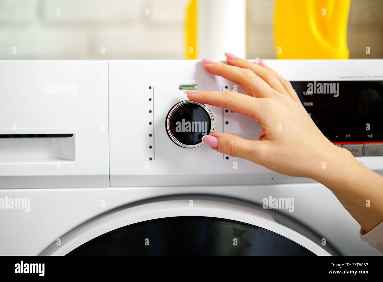 Woman Setting Washing Machine Cycle in Laundry Room Stock Photo - Alamy