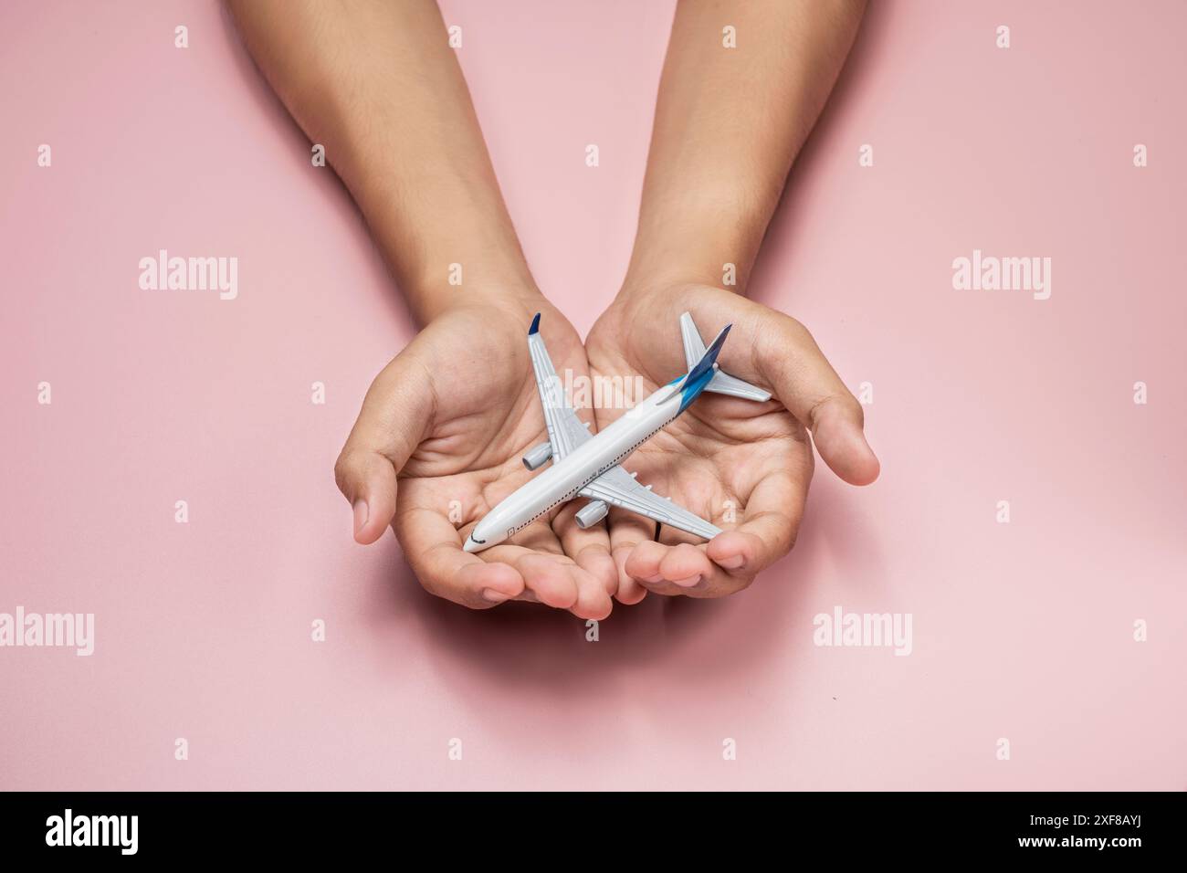A human hand showing a small passenger plane on his palm with a colored ...