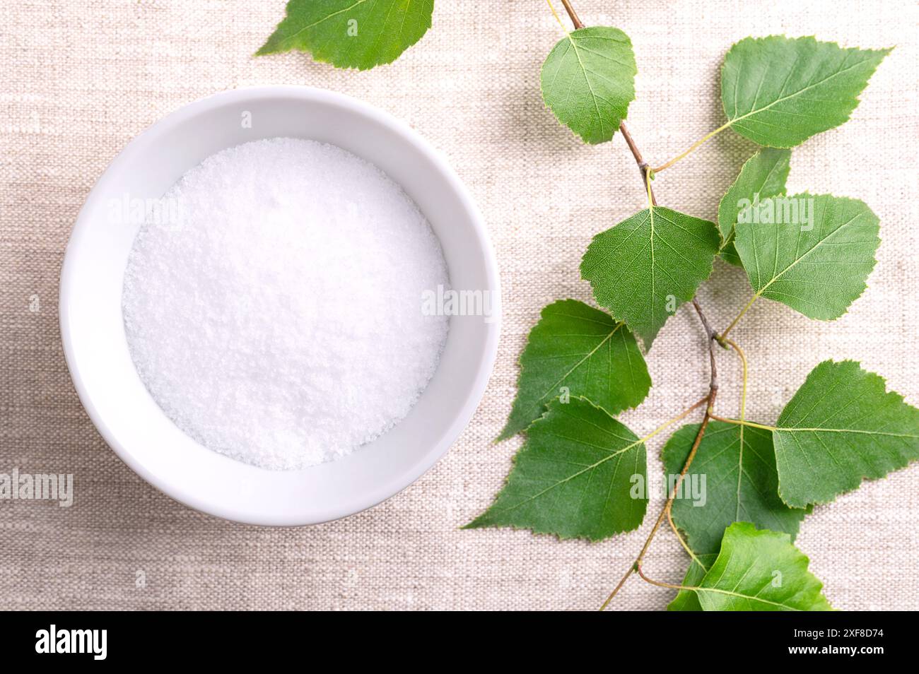 Birch sugar, table sweetener based on xylitol, in a white bowl on linen ...