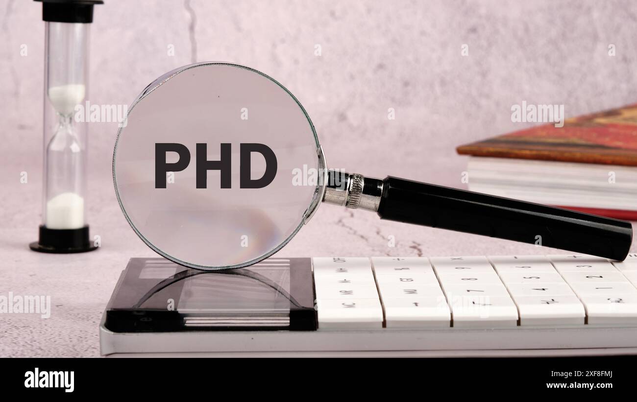 Text PHD written through a magnifying glass on a gray wall, front view ...