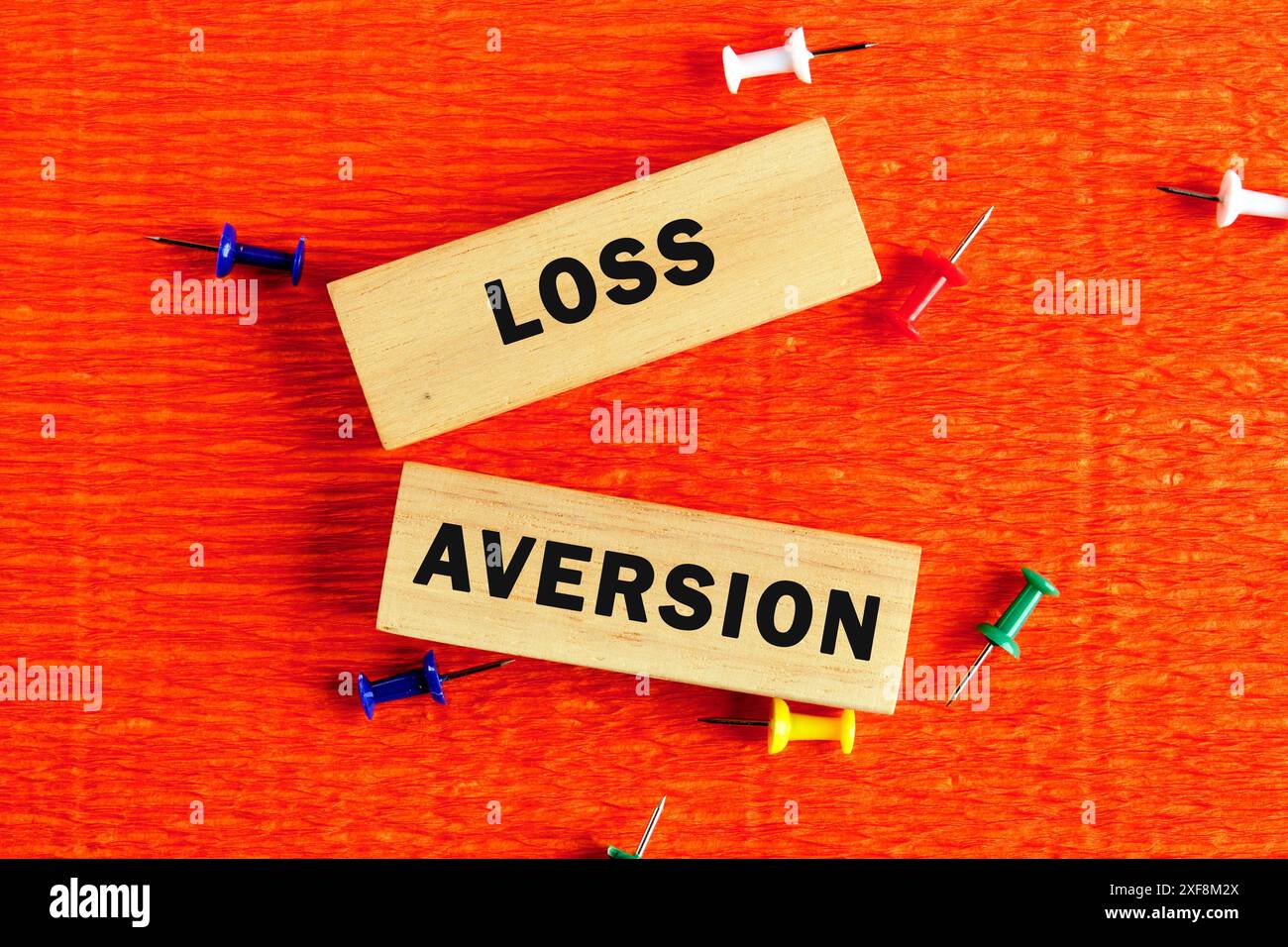 LOSS AVERSION text written on wooden blocks with a hand on an orange ...