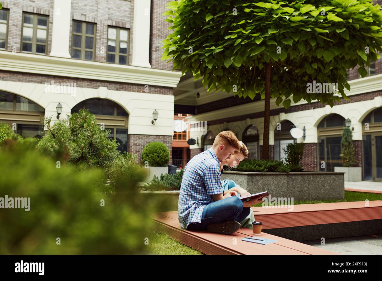 Modern university architecture. Young people, students sitting on bench ...