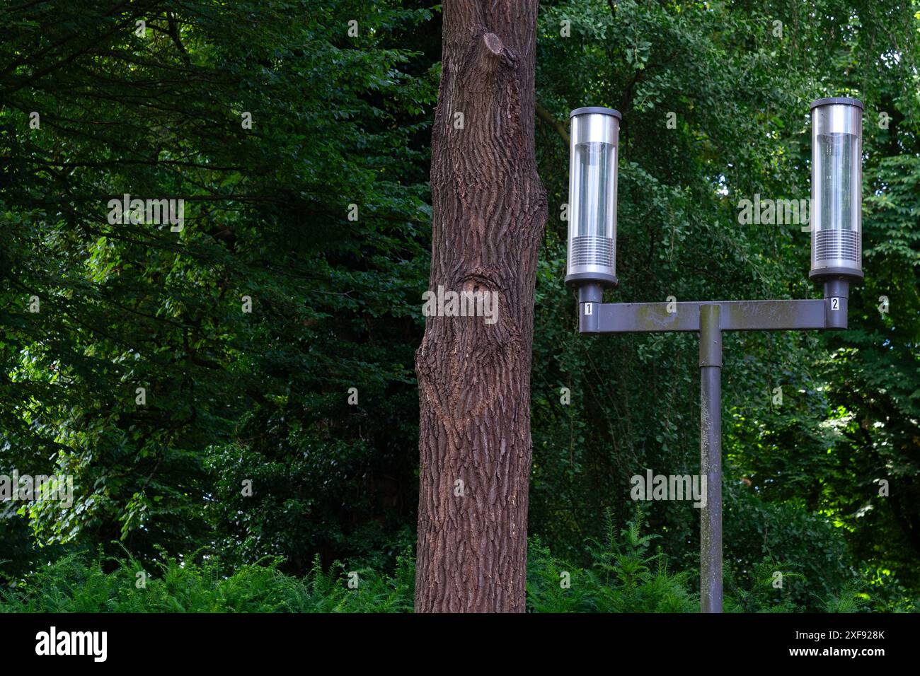 Two cylindrical streetlights, mounted on a metal post in the shaded ...