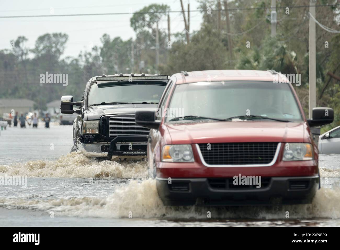 Hurricane flooded street with moving cars and surrounded with water ...