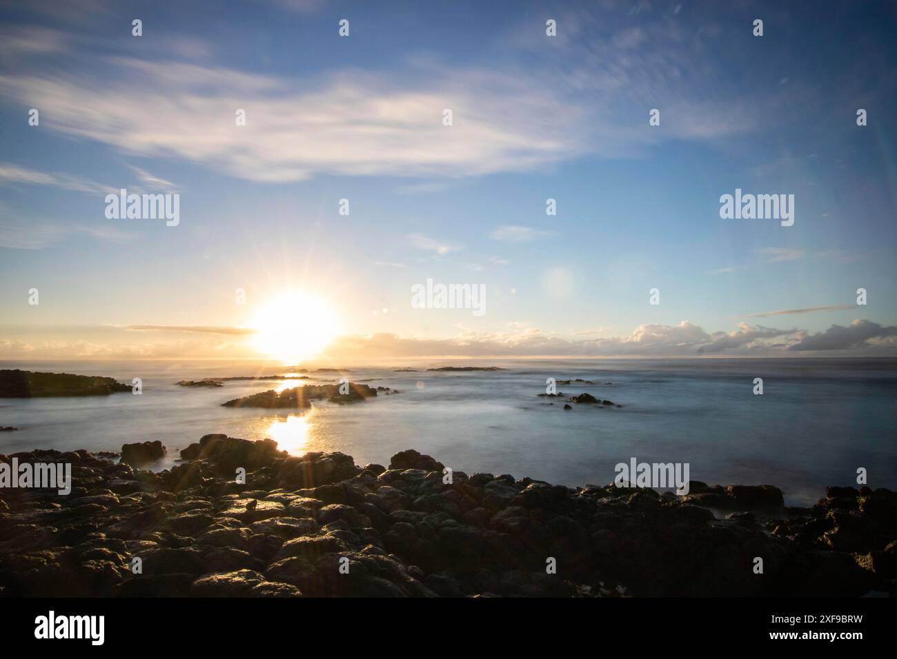 Sunrise over the sea, long exposure. sandy beach beach with lava stones ...