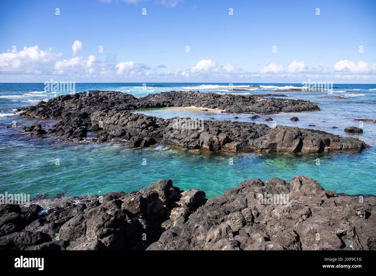 Beautiful lava beach during the day. Lava rocks alternate with crystal ...
