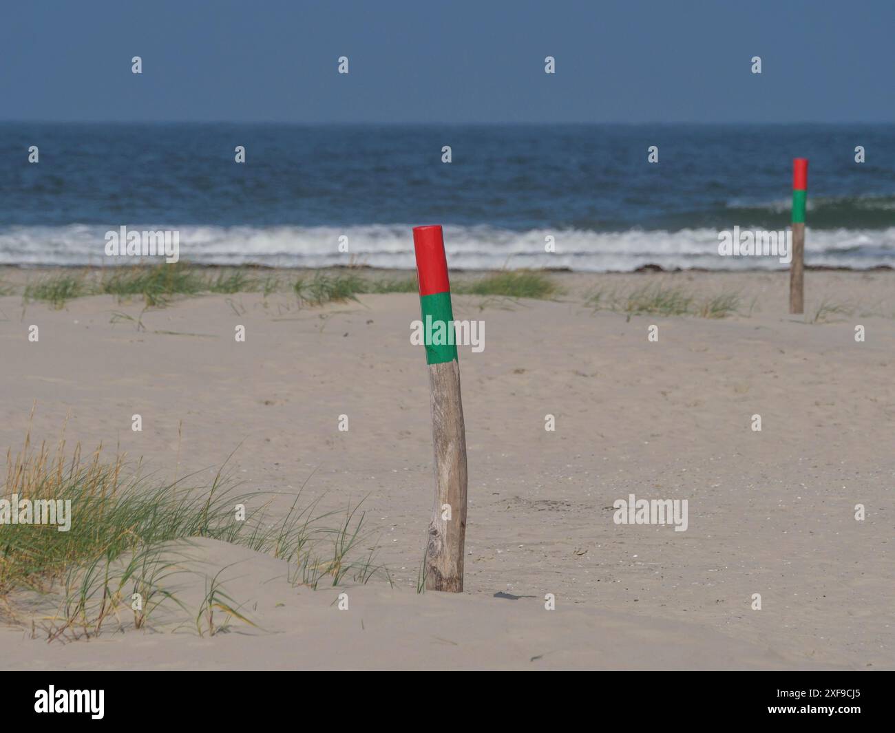 Sandy beach beach with wooden posts in red-green and view of the sea ...