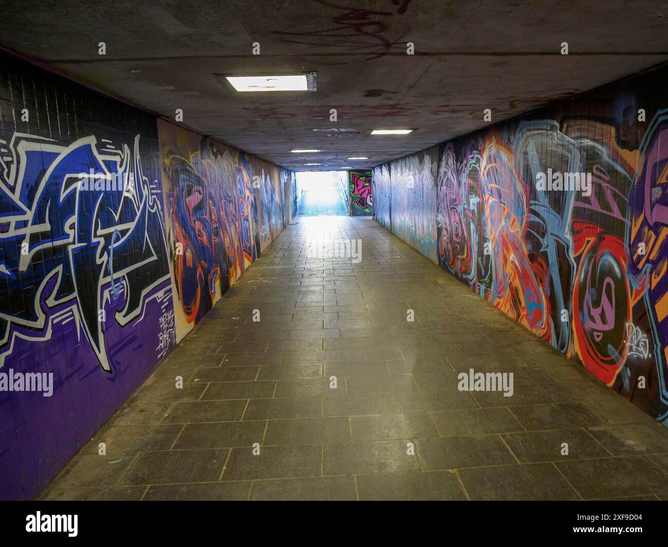 An urban tunnel with colourful graffiti on the walls leading to the ...