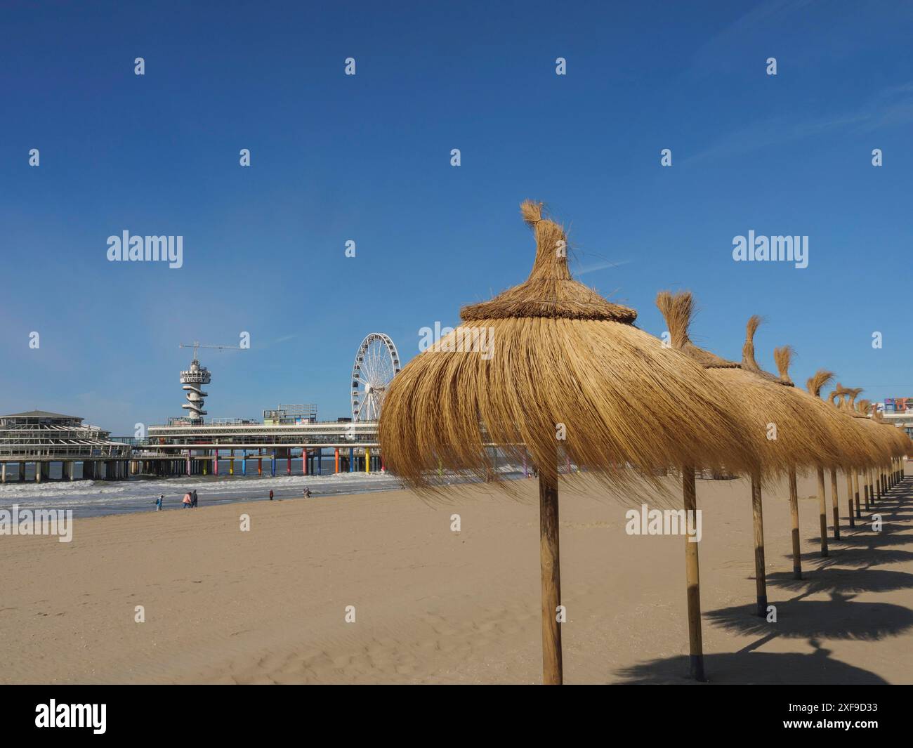 Beach with straw parasols, peaceful atmosphere and visible pier and ...