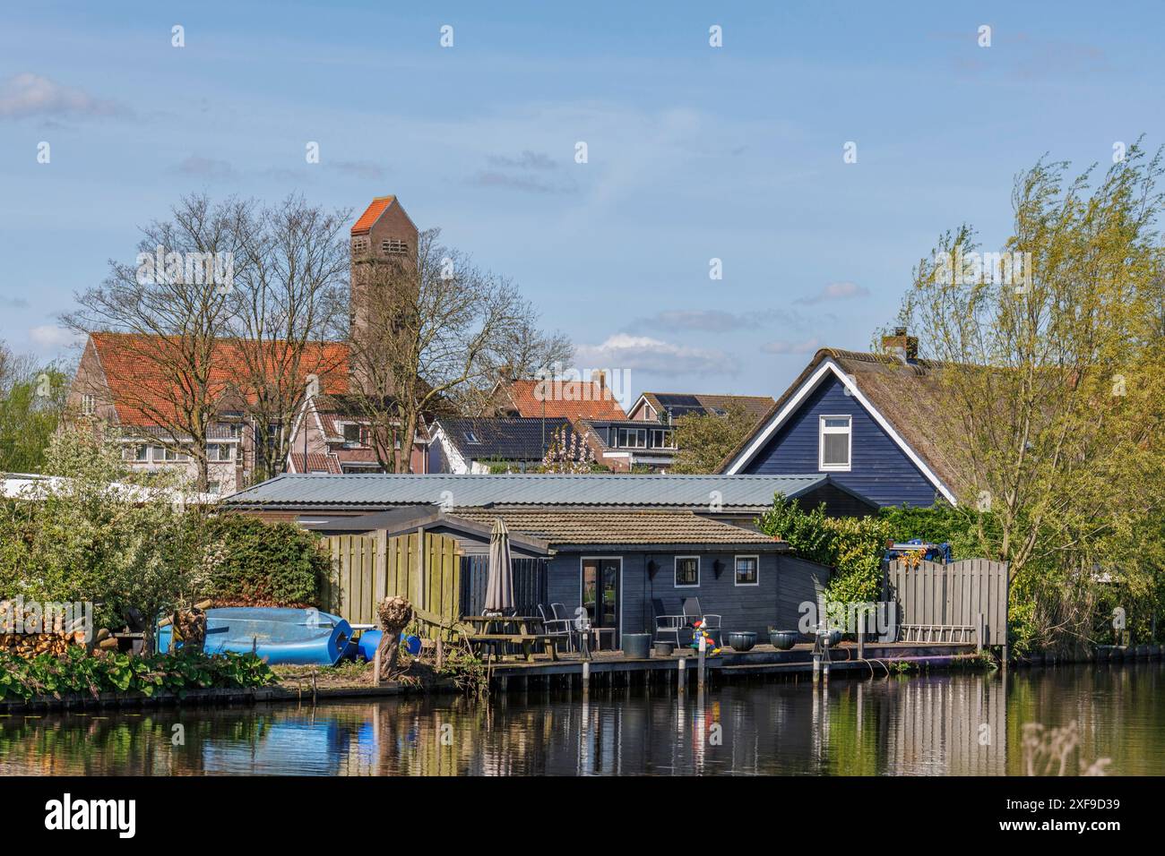 Picturesque riverside village with houses and trees under a blue sky ...