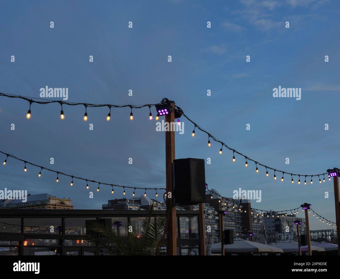 Strings of lights strung across an urban roof terrace at night create ...