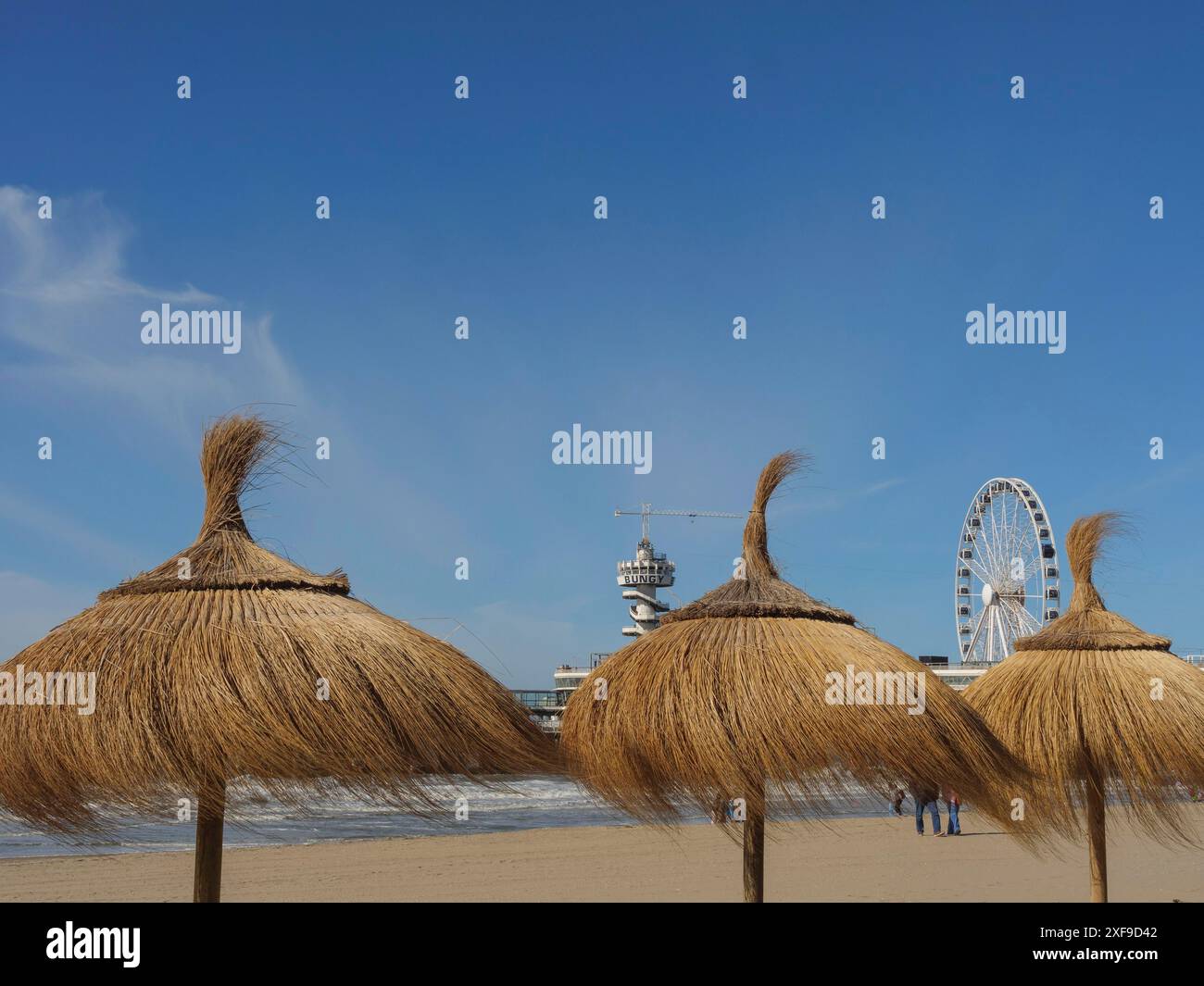 Maritime beach with wandering visitors, iconic straw umbrellas and a ...