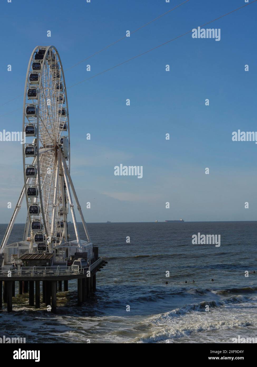 A Ferris wheel by the sea with calm waves and a blue sky, scheveningen ...
