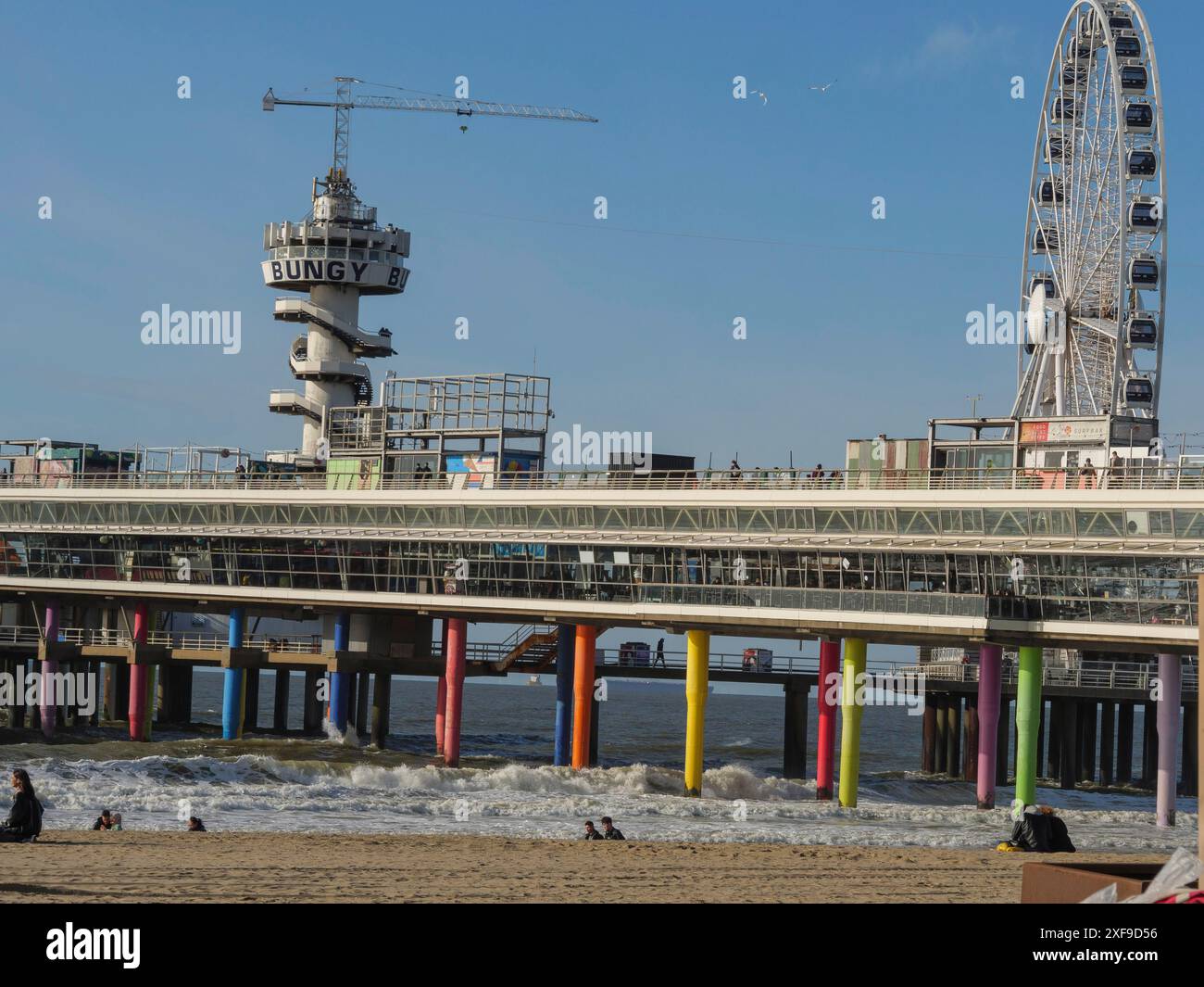 A pier with colourful columns, a Ferris wheel and a bungee tower on the ...