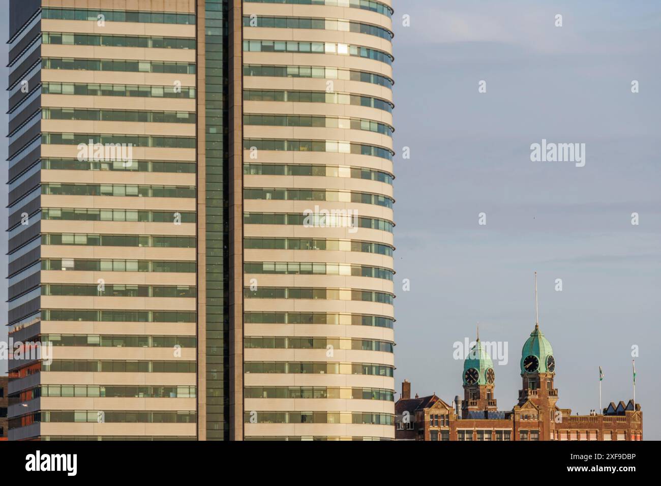 A modern skyscraper next to historic buildings, under a blue sky with ...