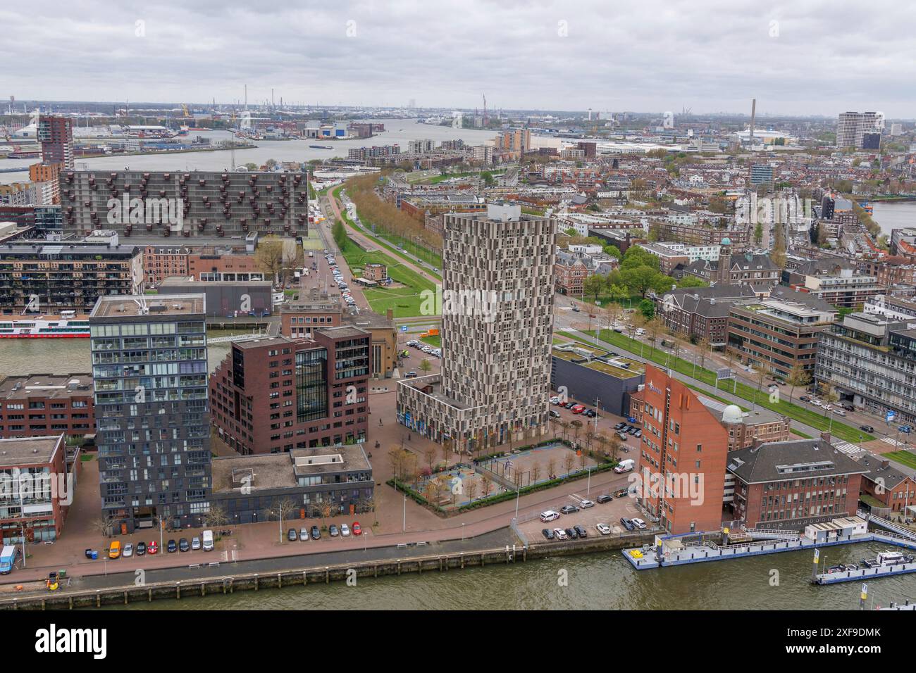 Aerial view of a city with modern buildings, streets and a harbour under a cloudy sky, Rotterdam ...
