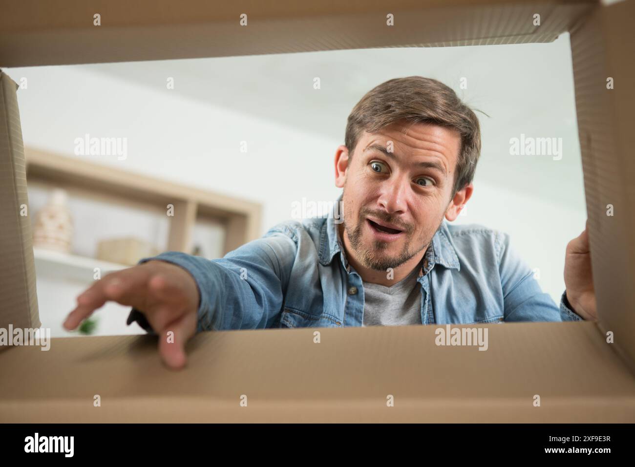 young handsome smiling reaching for something inside of a box Stock ...