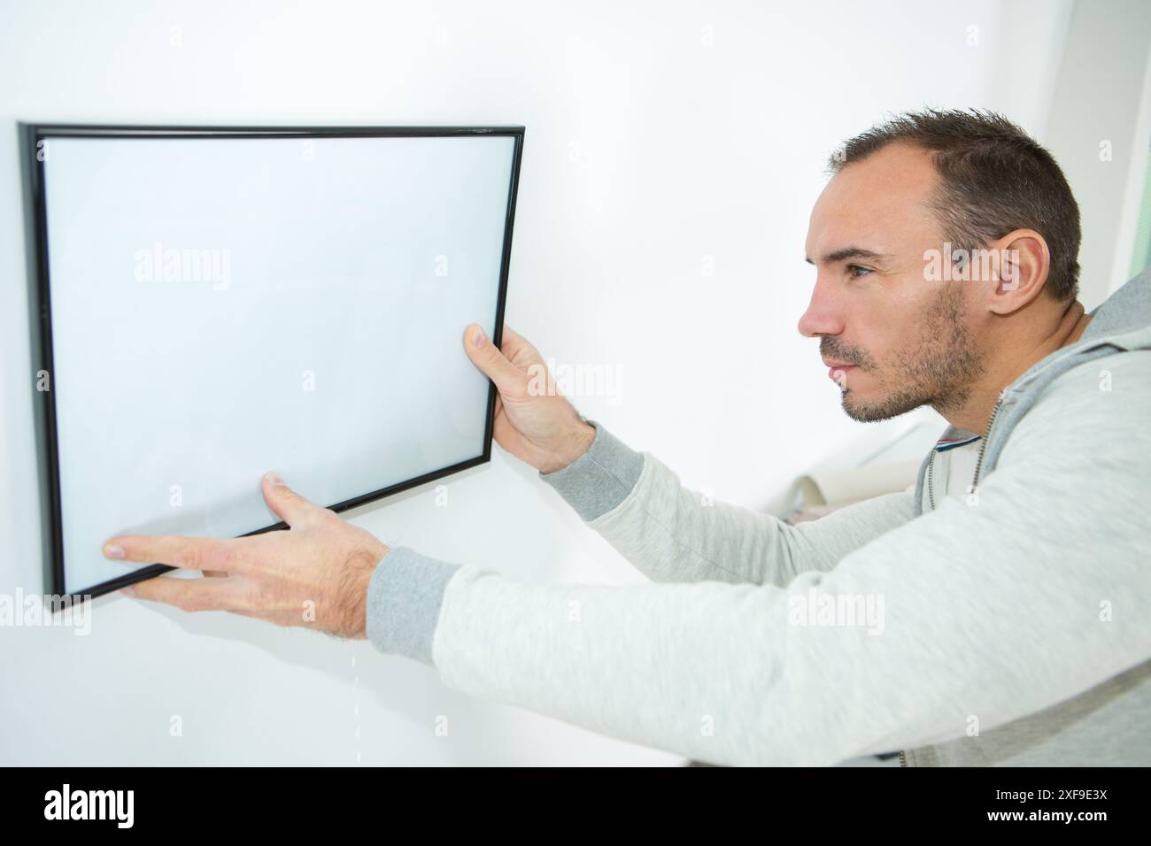 man hanging a blank frame on the wall Stock Photo - Alamy